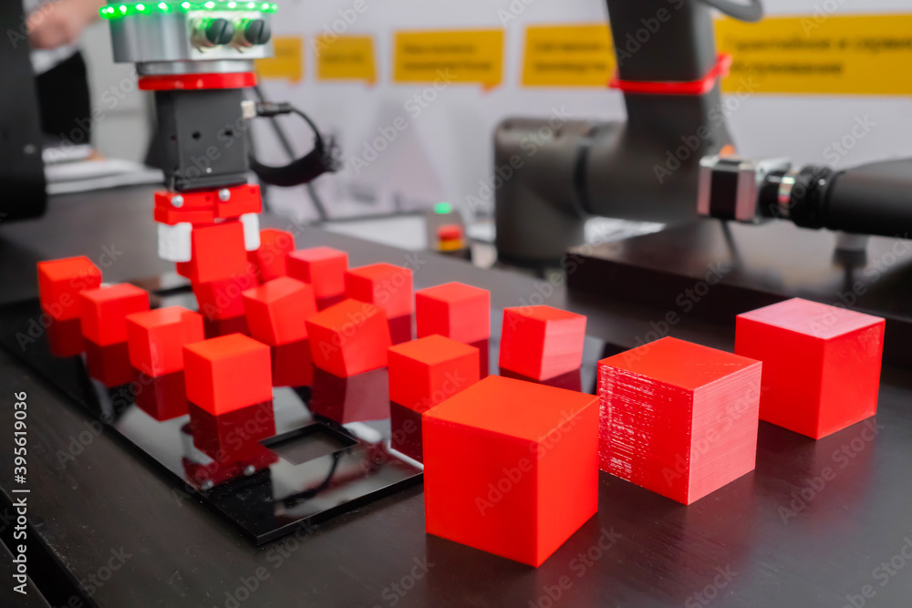 Pick and place robotic clamp arm manipulator moving red toy blocks at modern robot exhibition ...