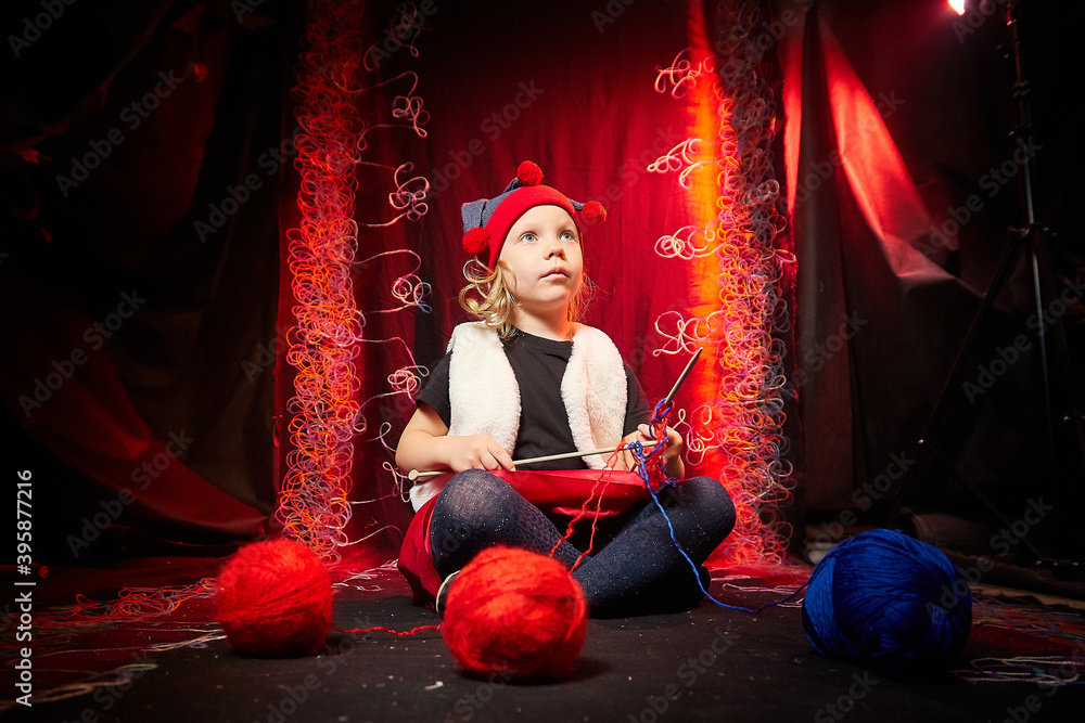 A pretty little girl who looks like a dwarf or elf is knitting with ...