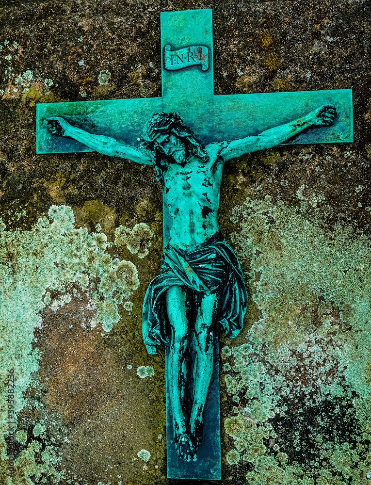 Jesus Christ crucified on metal cross covered in moss.Jesus crucified on the stone grave ...