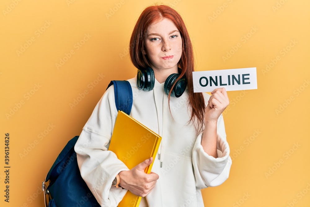 Young red head girl wearing backpack holding online banner puffing ...