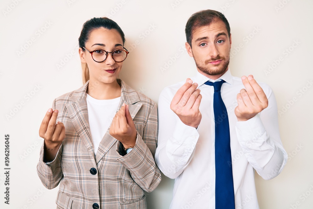 Beautiful couple wearing business clothes doing money gesture with ...