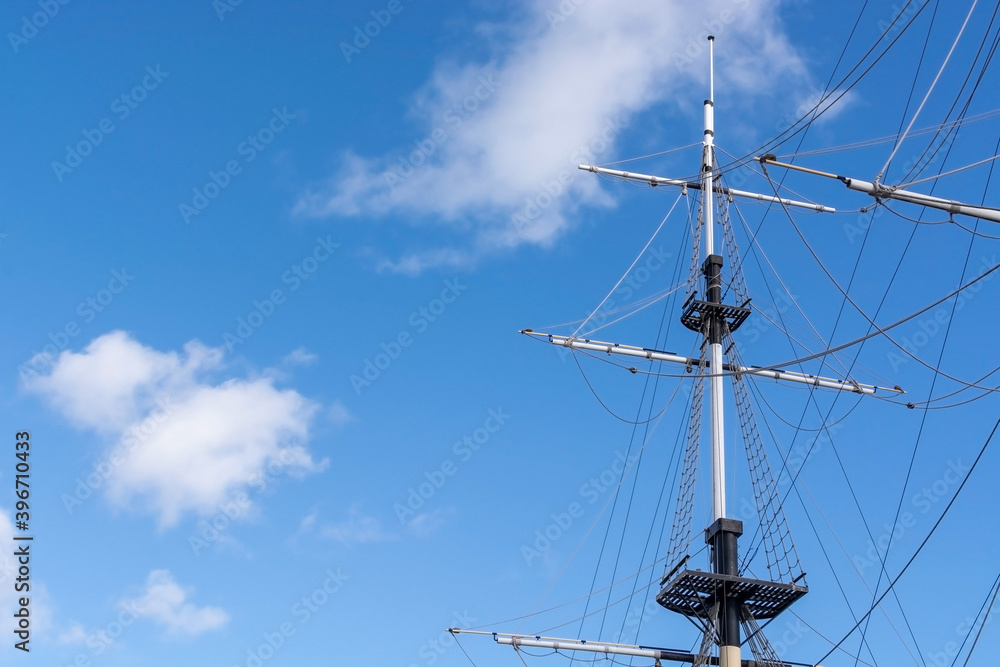 Old hip sailing mast against a blue sky with clouds background with ...