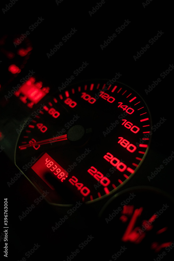 Speedometer with red light at night close-up. Car dashboard. Vertical ...