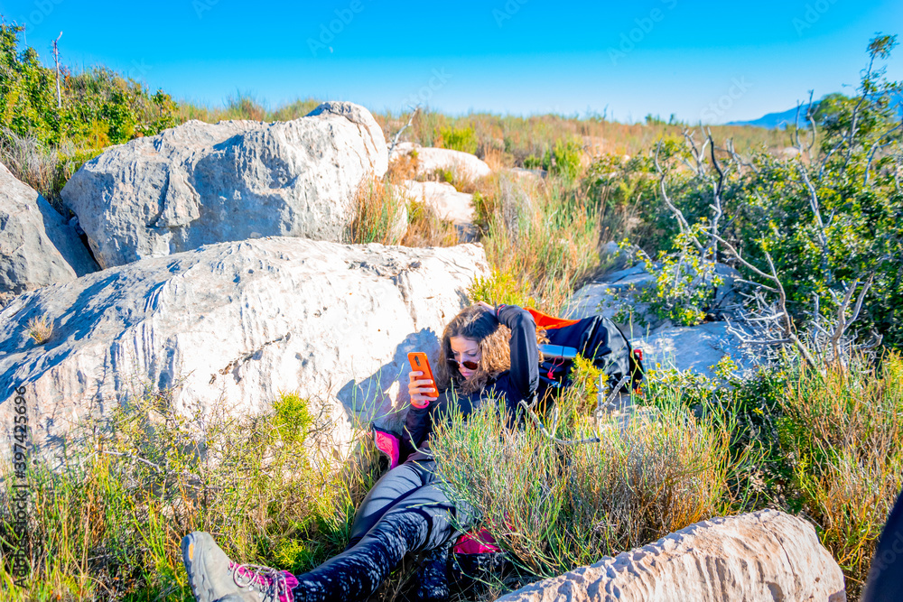 Mujer joven descansado y haciendo fotos después de la ruta senderista ...