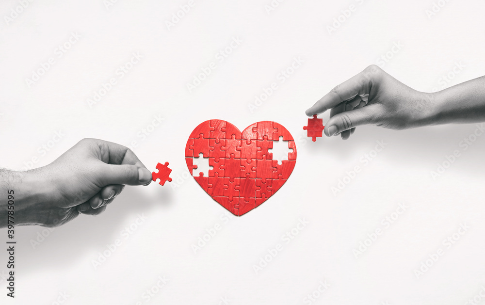 Two people put together a heart-shaped puzzle. The concept of building ...