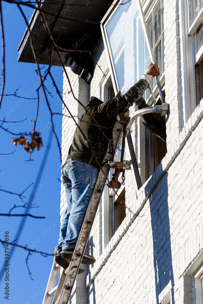 A hispanic repair man wearing jeans and sneakers is on top of a ...