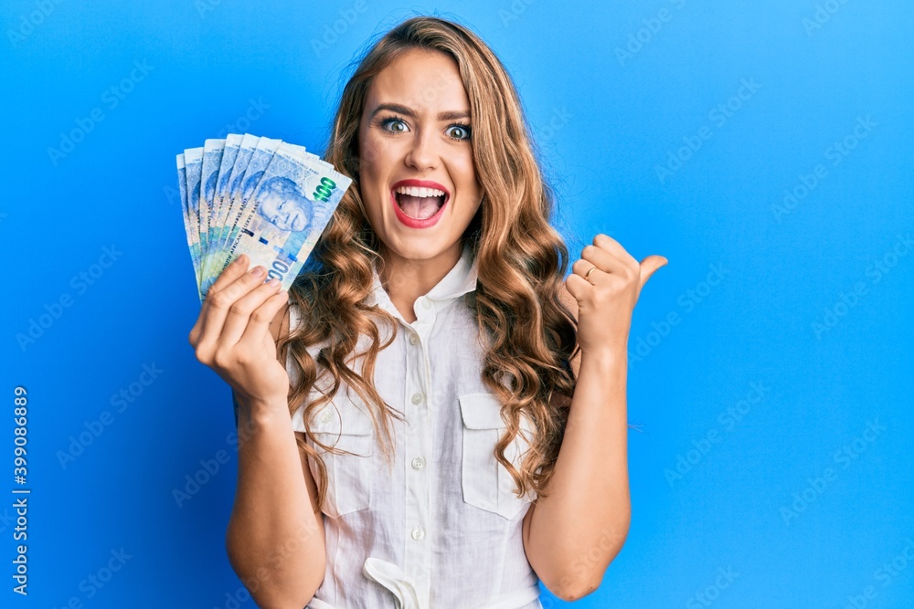 Young blonde girl holding south african 20 rand banknotes pointing ...