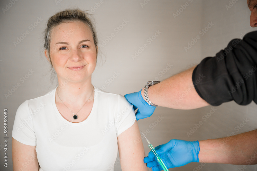 Foto de Stock Doctor injecting Covid Vaccine into a young blonde womans ...