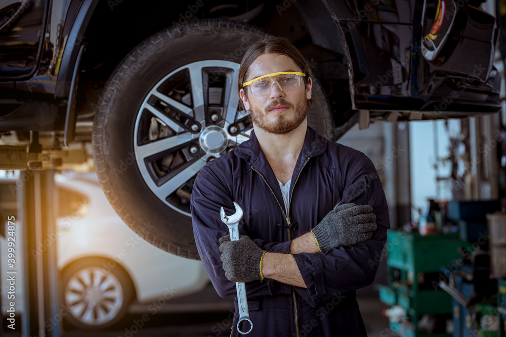 Car mechanic under checking car wheels at garage for maintenance or ...