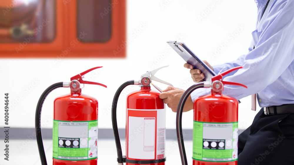 Fire engineer checking pressure gauge level of fire extinguishers tank ...