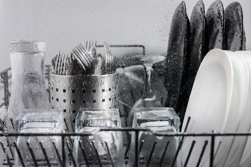 dishes and cutlery in the dishwasher tray in a splash of water. Washing ...