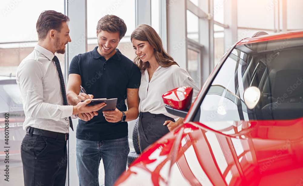 Delighted couple and manager signing papers in car dealership Stock ...