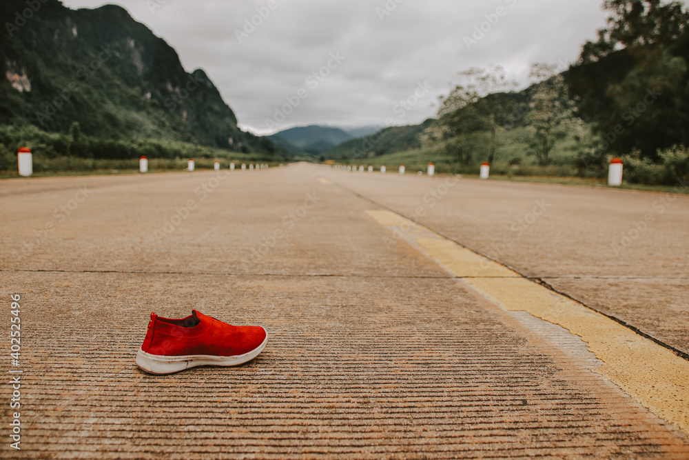 Conceptual photo of a single red shoe left behind in the middle of a ...