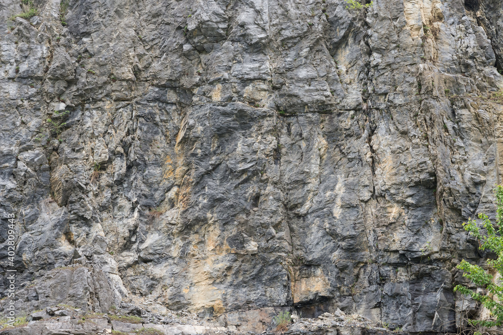 Weathered rock face texture in old stone pit with parts of green. Aged ...