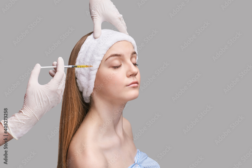 Cheek injection at spa salon. Doctor hands. Pretty female patient ...