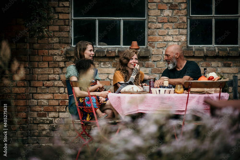 Smiling friends talking while eating vegetable at backyard Stock Photo ...