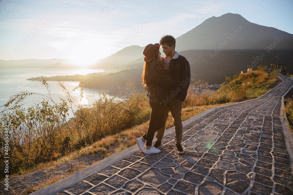Hispanic couple seeing each other with sunrise at Lake Atitlan behind ...