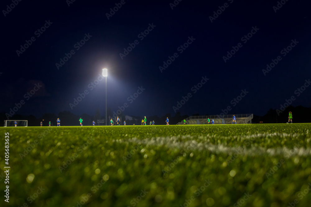 Stadium lights illuminate a soccer field. Stock Photo | Adobe Stock