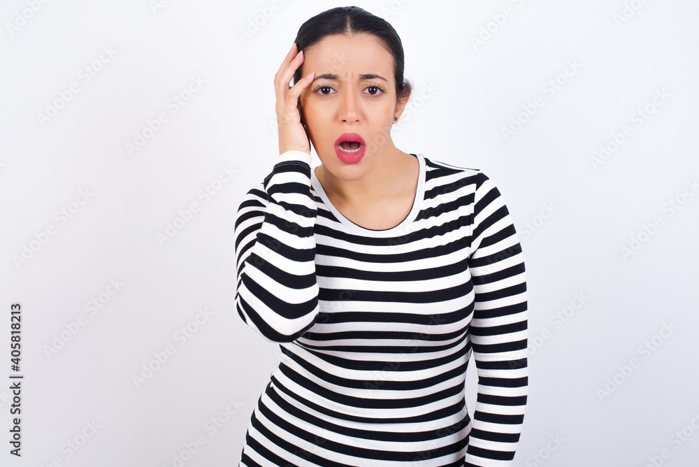 Embarrassed Young beautiful woman wearing stripped t-shirt against ...