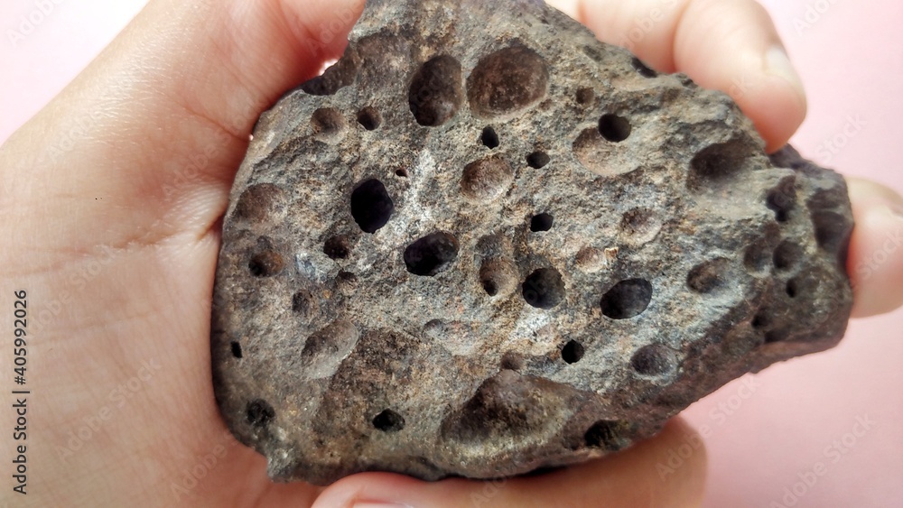 Extrusive volcanic igneous rock, vesicular basalt. Dark brown and ...