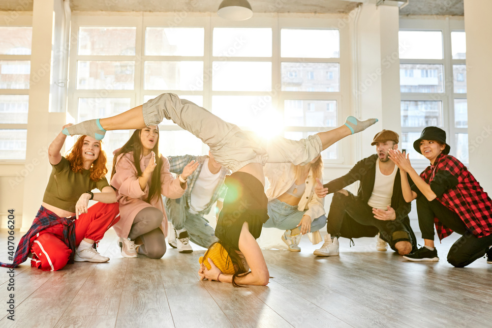 female break dancer stands on her hands, legs raised up while dancing ...