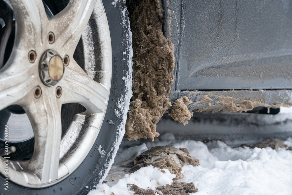 Adhered to the body of the car dirty snow from the road, close-up ...
