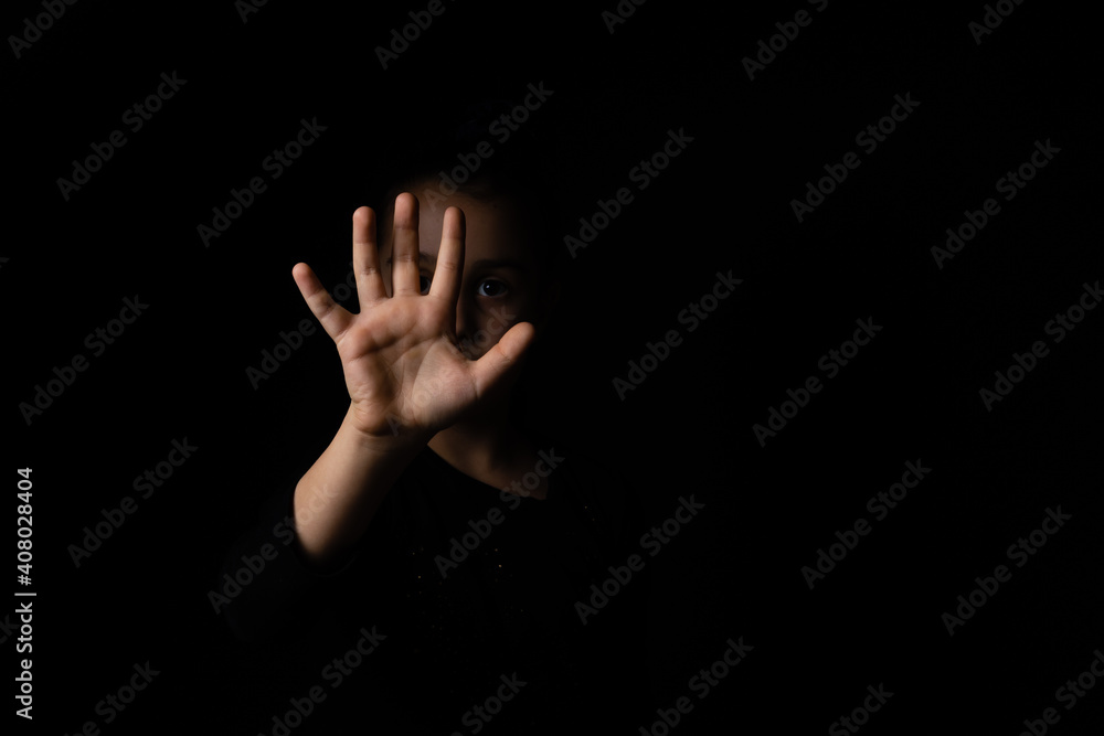 little girl with a raised hand making a stop sign gesture on a black ...