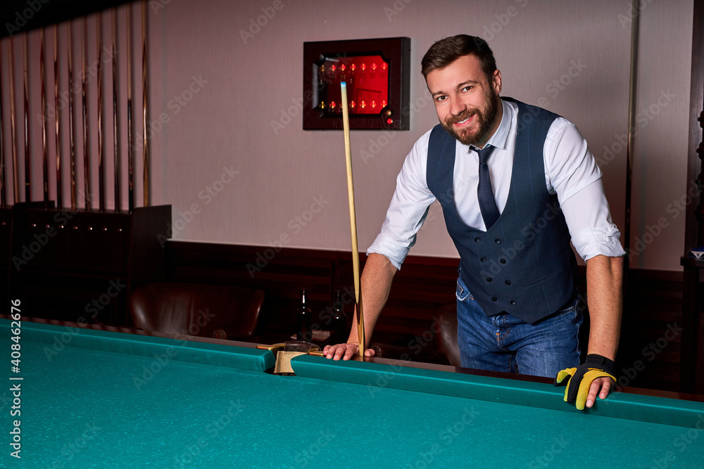 smiling male standing next to billiards table, looking at camera ...