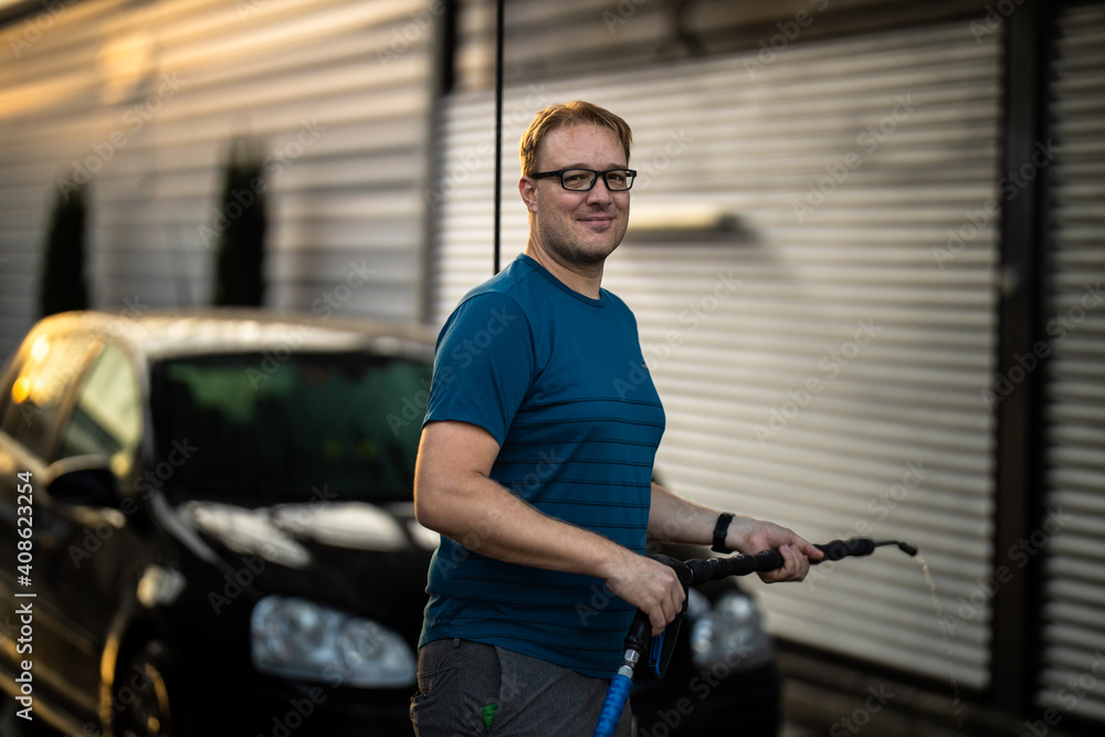 Young man washing his beloved car carefully in a manual car wash to ...
