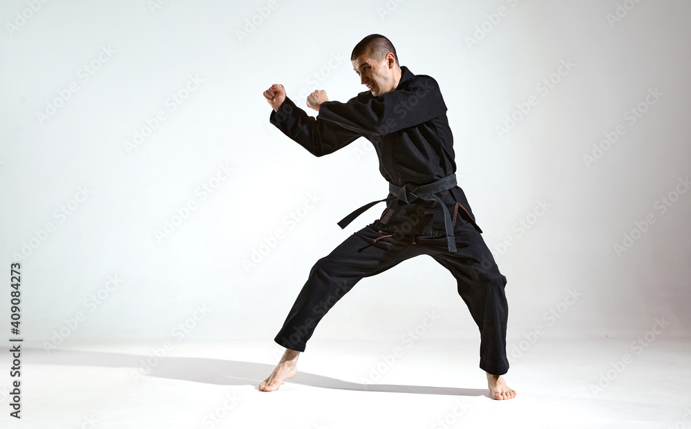 Fighting man in black kimono fighter shows karate technique on studio ...