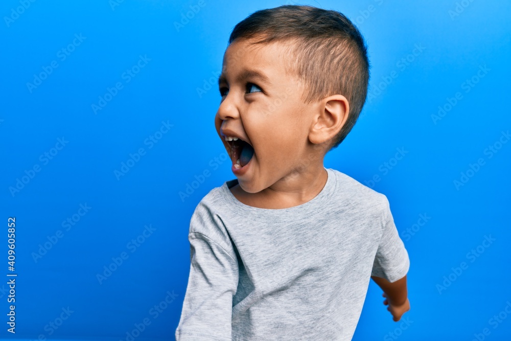 Adorable latin toddler smiling happy standing over isolated blue ...