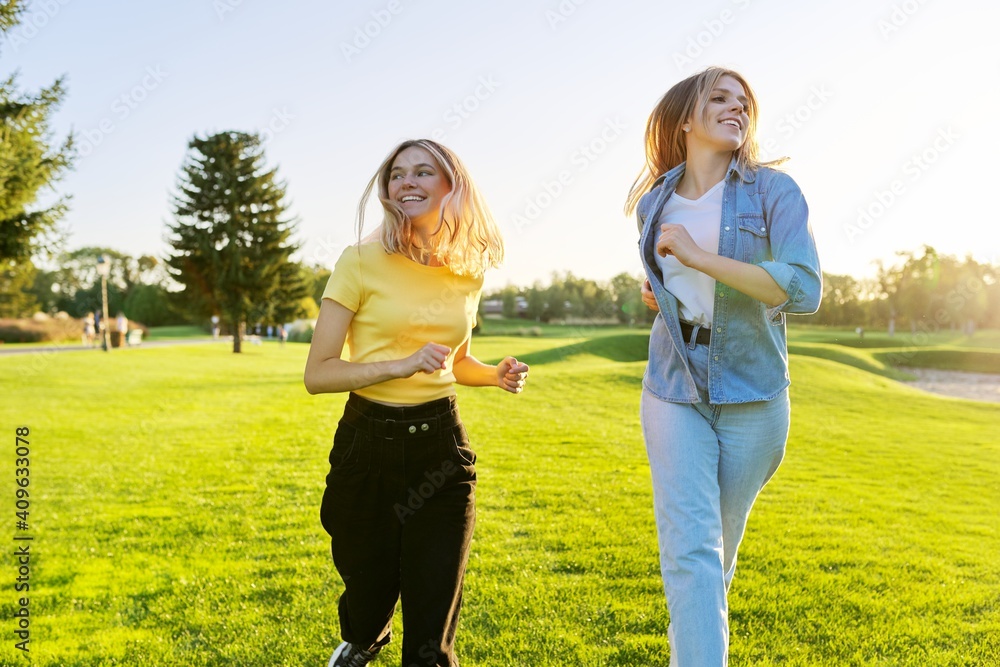 Beautiful active running young women, green lawns of the park at sunset ...