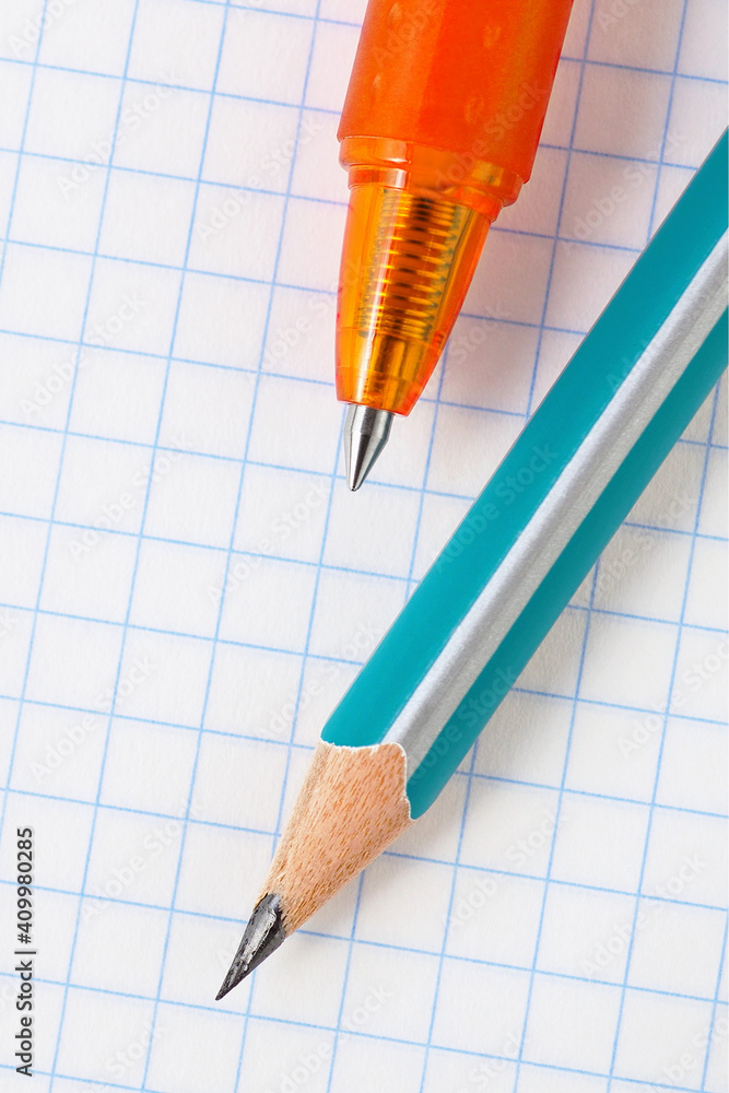 Foto Wooden pencil and orange pen lie on a blank squared notebook sheet ...