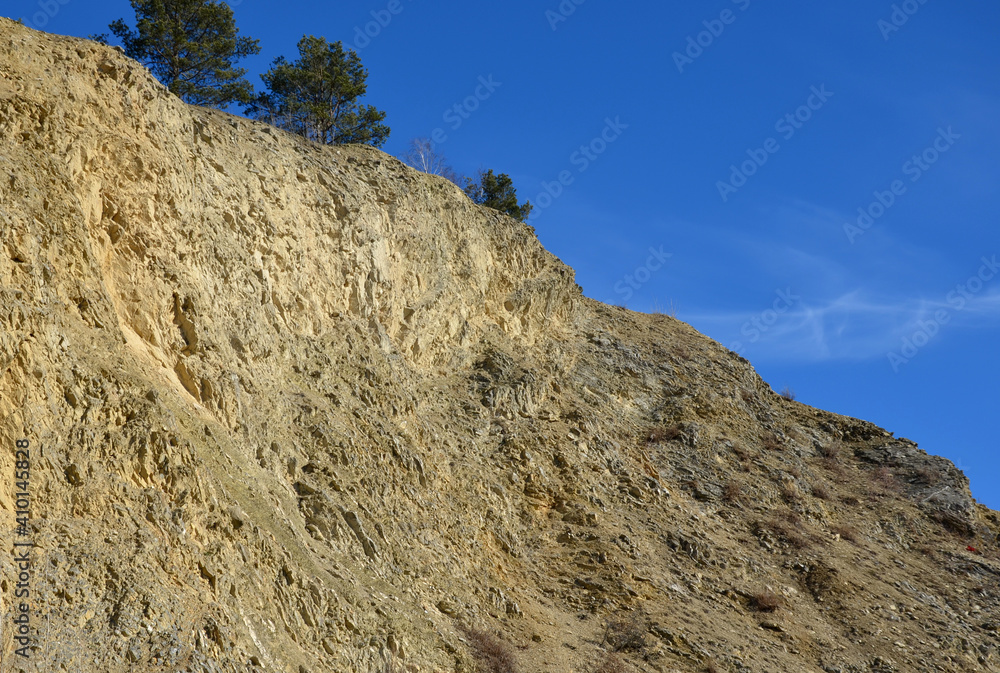 limestone cliff with pine trees on top of a rock. yellow weathered ...