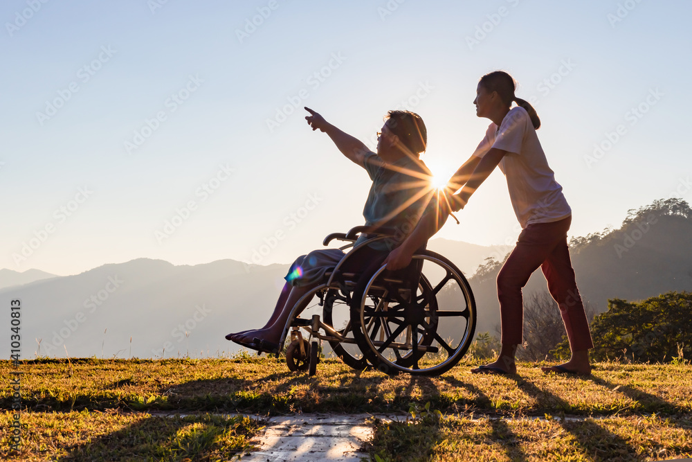 Disabled handicapped young man in wheelchair walking with his care ...