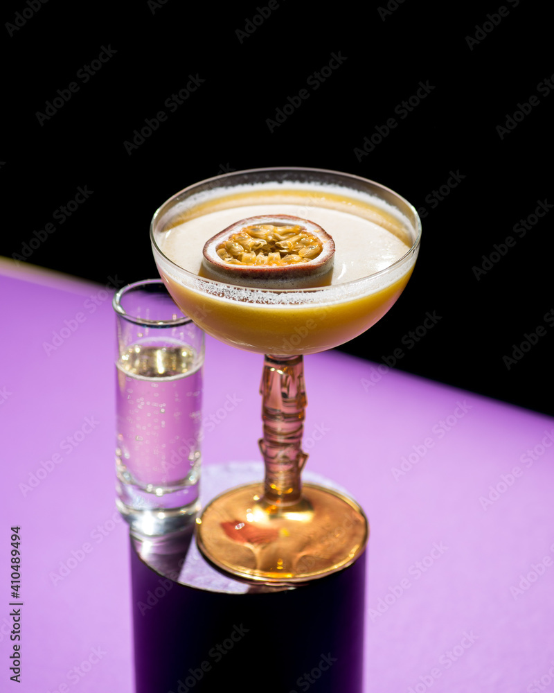 yellow tropical cocktail with passion fruit and shot on a background of ...