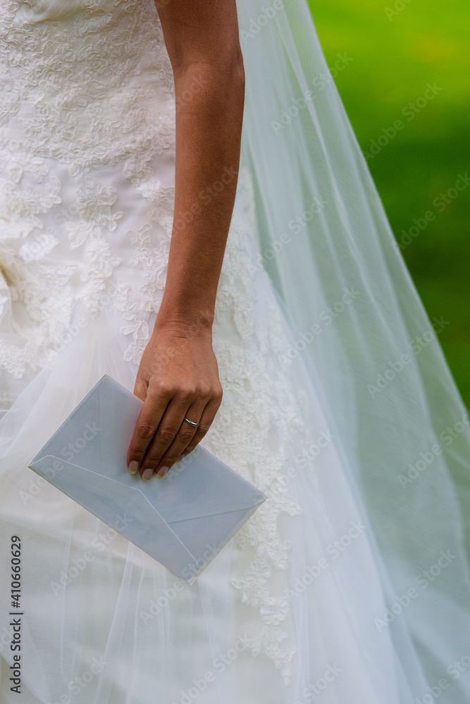 Hand of the bride holding an enveloppe from a guest and wedding ring at ...