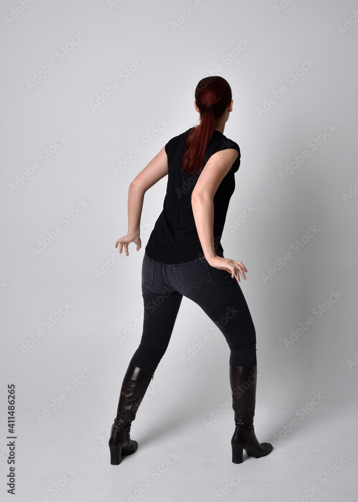 Simple full length portrait of woman with red hair in a ponytail ...