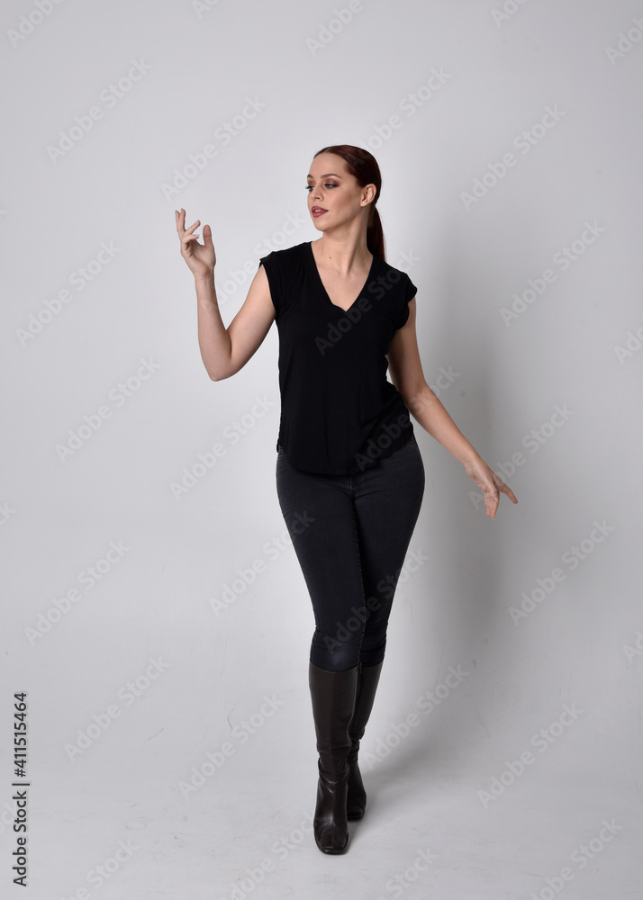 Simple full length portrait of woman with red hair in a ponytail ...