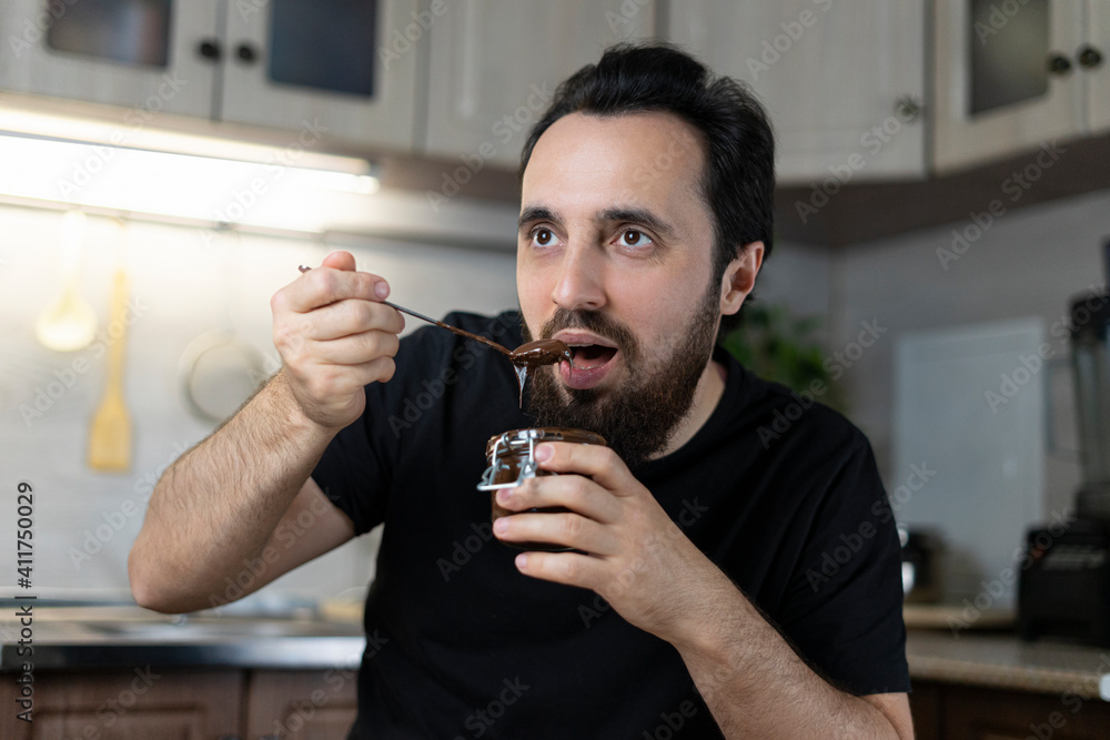 Strong brutal man eats emotionally chocolate paste. Men spread ...