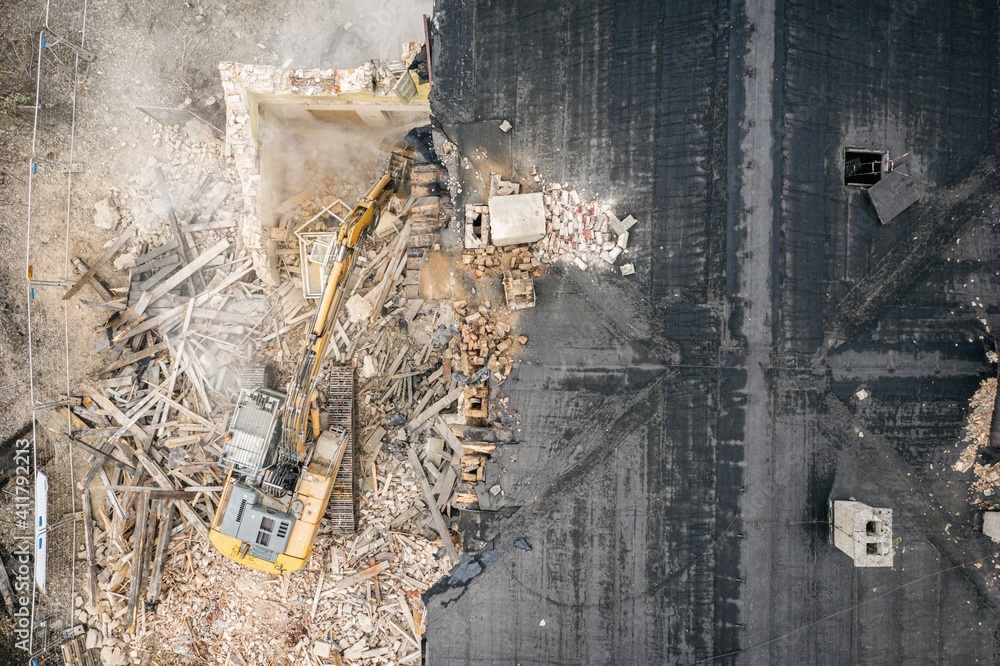 Yellow excavator destroys building. Heavy duty machine is demolishing a ...