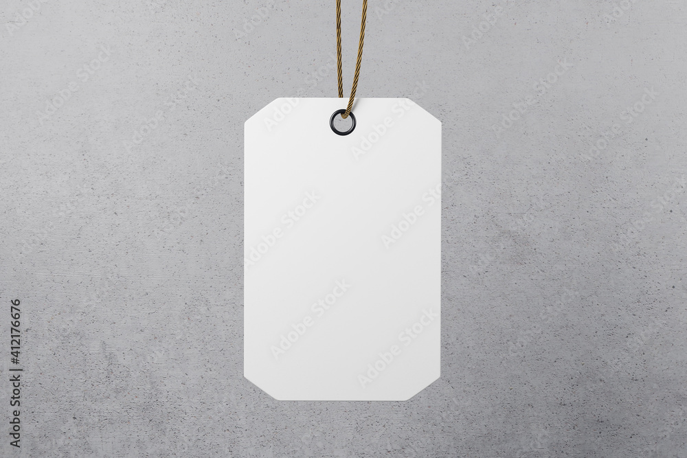 Blank white label tag on string at light concrete wall background. Eco ...