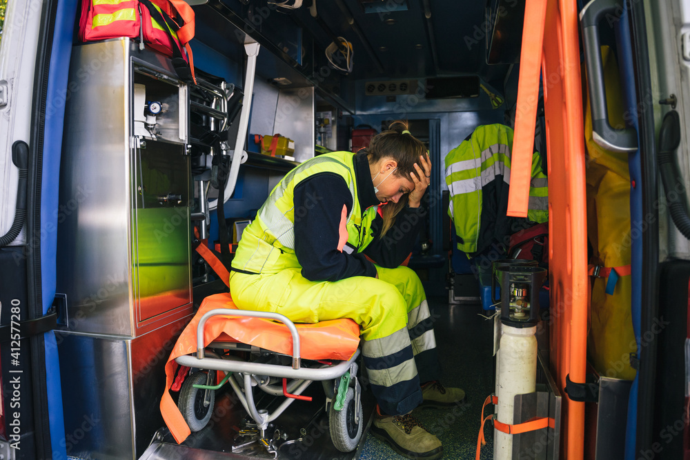 Portrait of paramedic in an ambulance sitting on a litter, with his ...