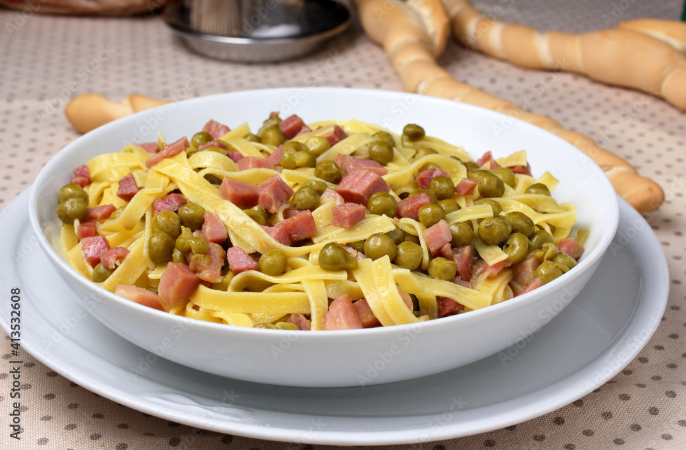 Piatto di tagliatelle con piselli e prosciutto cotto. Tavola ...