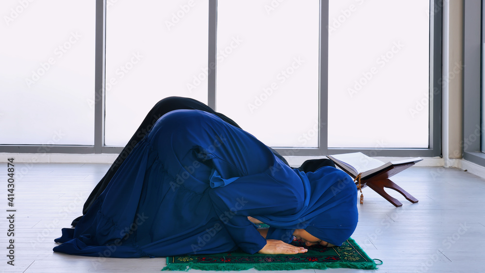 Two Asian Muslim young women in traditional hijab are praying glorify ...