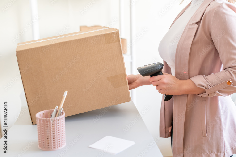 Woman employee of post office scanning parcel using barcode scanner to ...