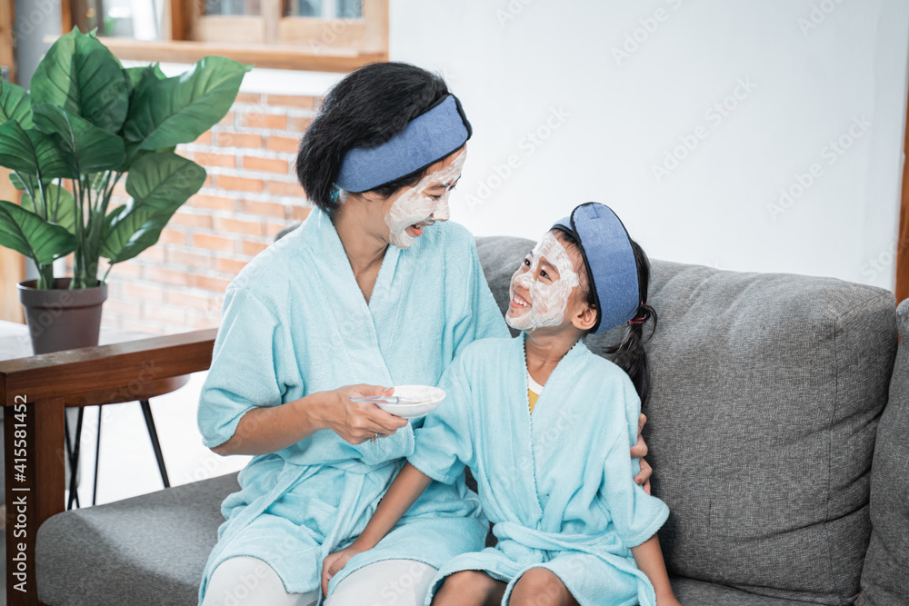 a mother and her little girl wearing face masks stare at each other while sitting on the sofa in ...