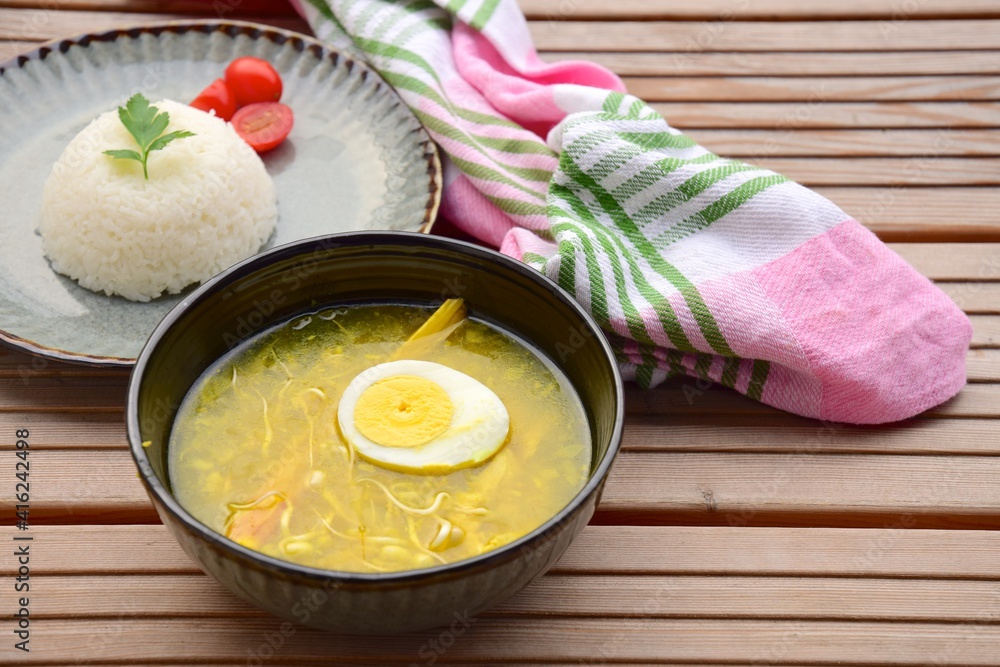 Soto Ayam, yellow spicy chicken soup with egg, tomato, bean sprouts and ...