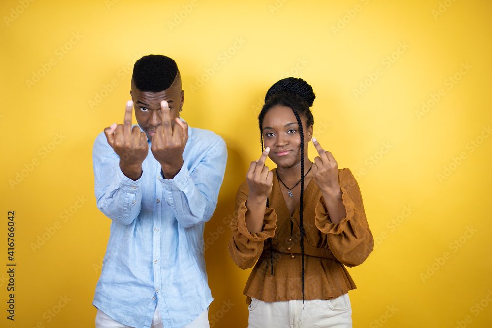 Young african american couple standing over yellow background showing ...