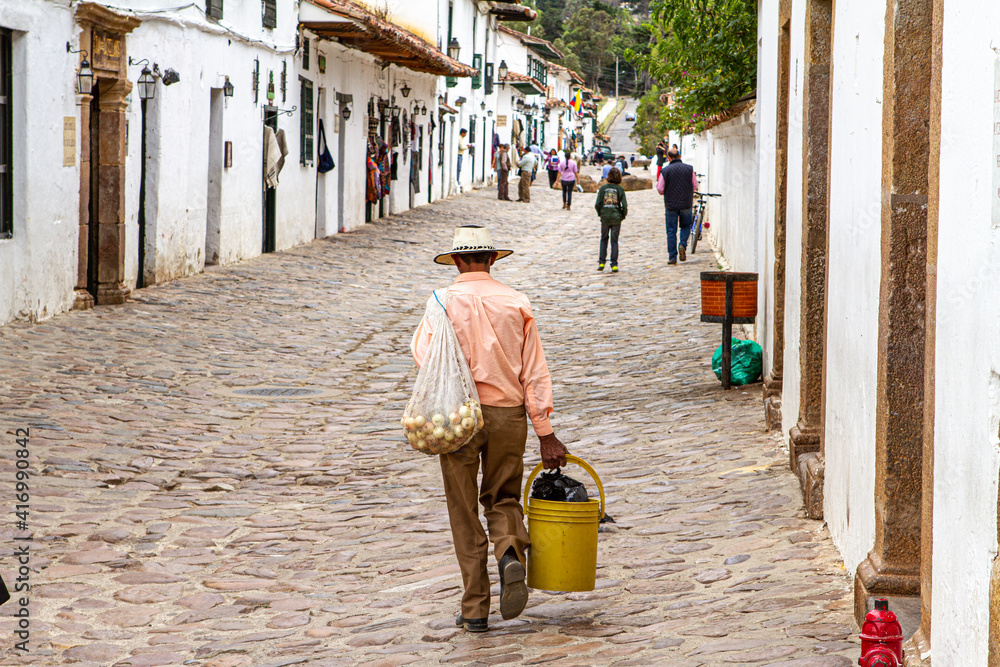 Colombian native farmer, wearing hat. walking with sacks vegetables ...